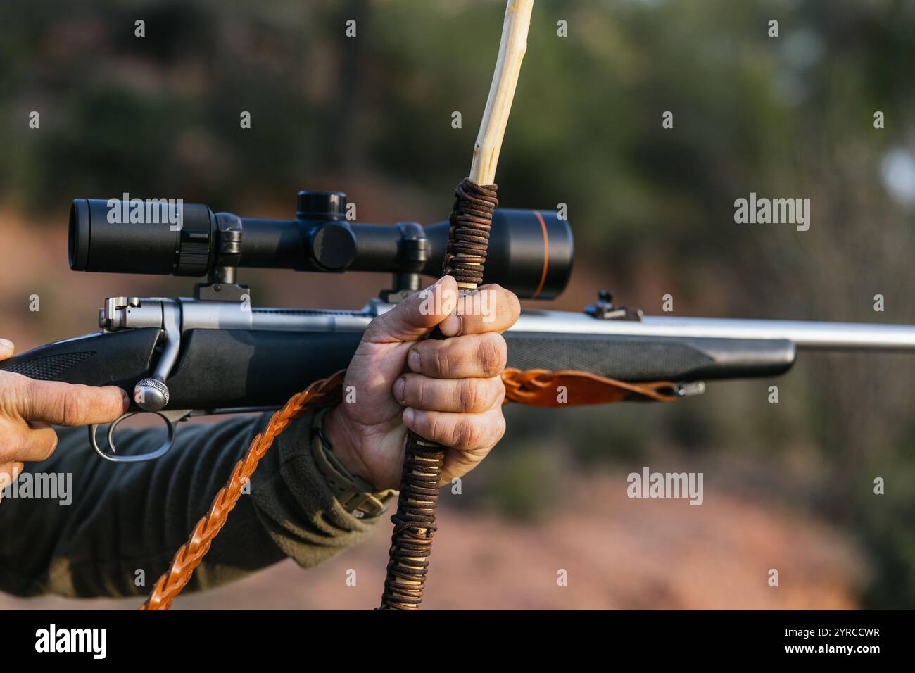 Hunter holding rifle with scope and monopod in forest Stock Photo - Alamy
