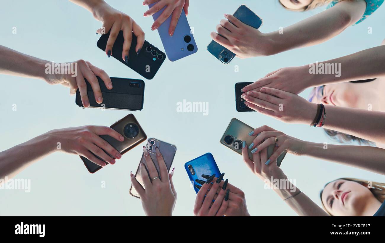 Group of friends holding smartphones making a circle with mobile phones ...
