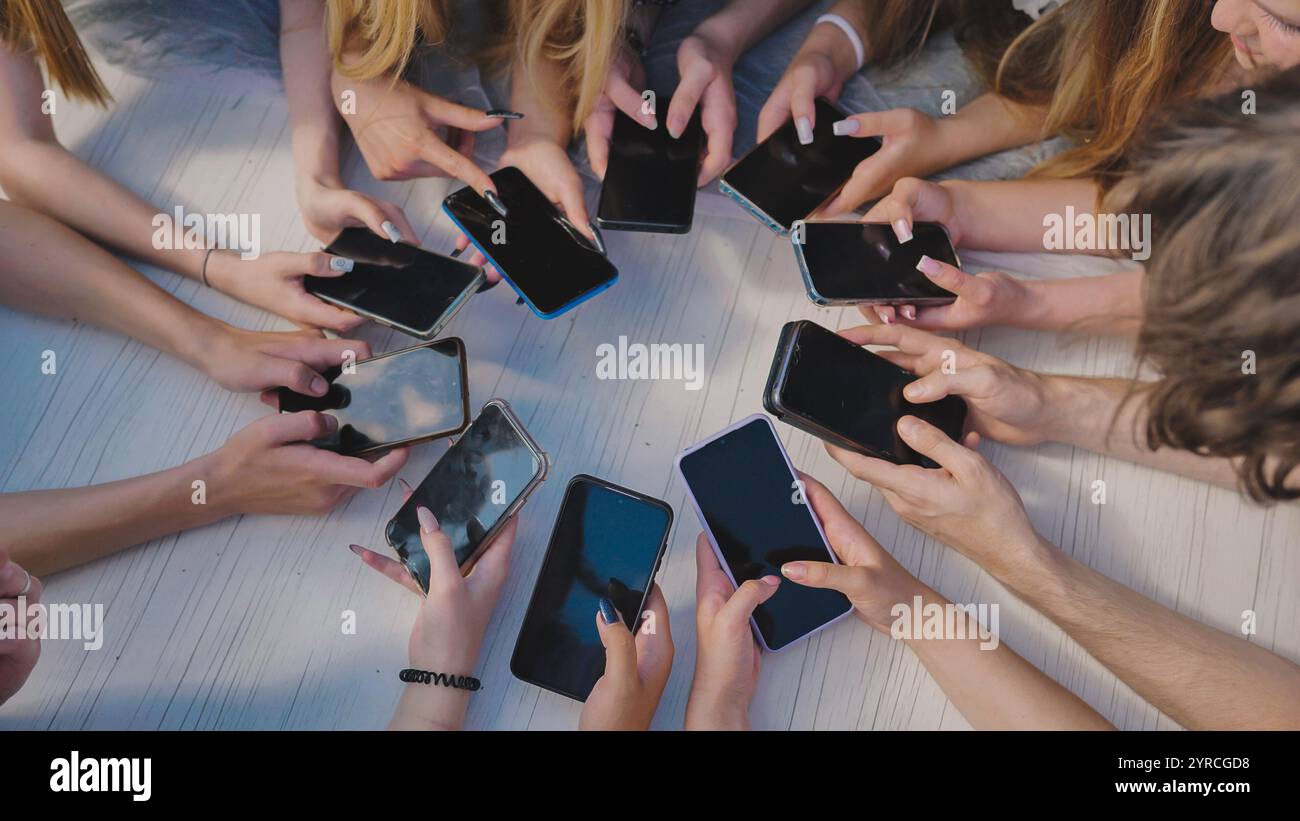 People holding their smartphones around a white table, using their ...