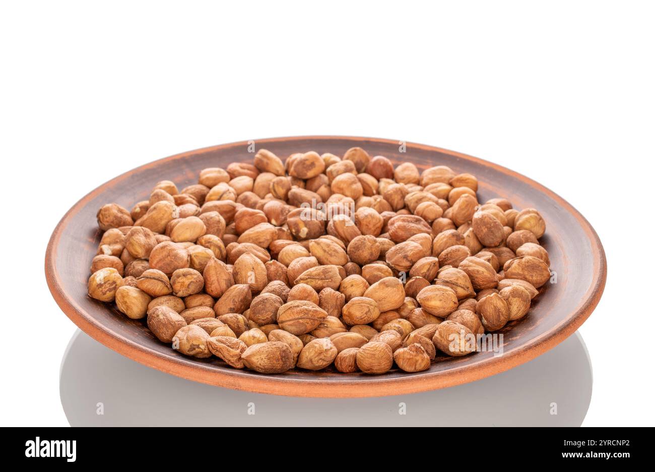 Shelled hazelnuts on a clay plate, close-up, isolated on a white ...