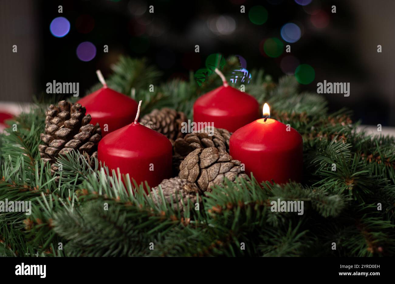 Close up of an advent wreath with one red burning candle on white table ...
