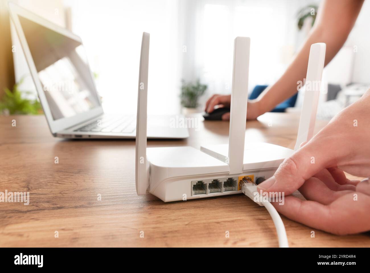 Person connecting modern wi-fi router on light table in living room ...