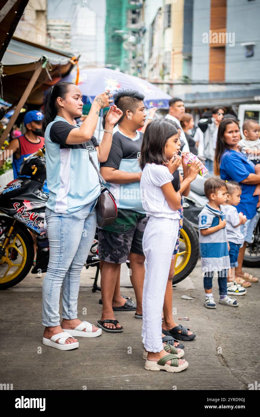 Crowds of Filipino children and parents watch the religious festival make its way past their ...
