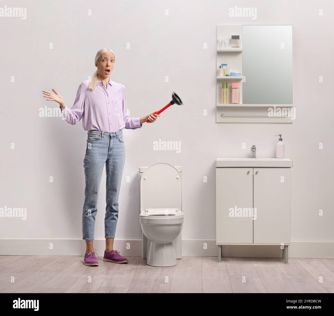 Shocked woman in a bathroom holding a toilet plunger Stock Photo - Alamy
