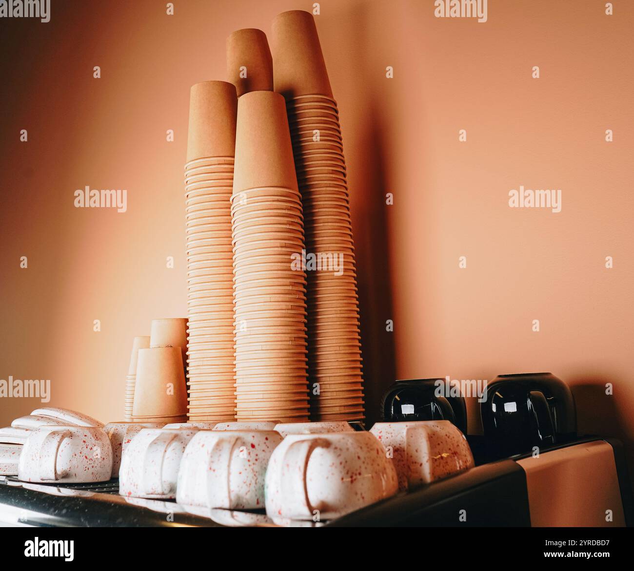 A group of paper cups sits atop the coffee machine, their vibrant ...