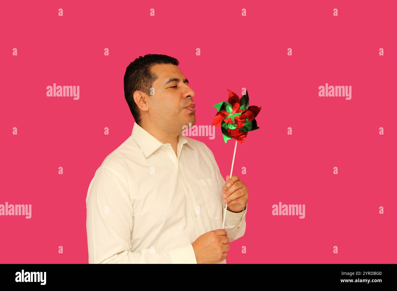 40-year-old dark-skinned Mexican man blows to spin a tricolor pinwheel ...