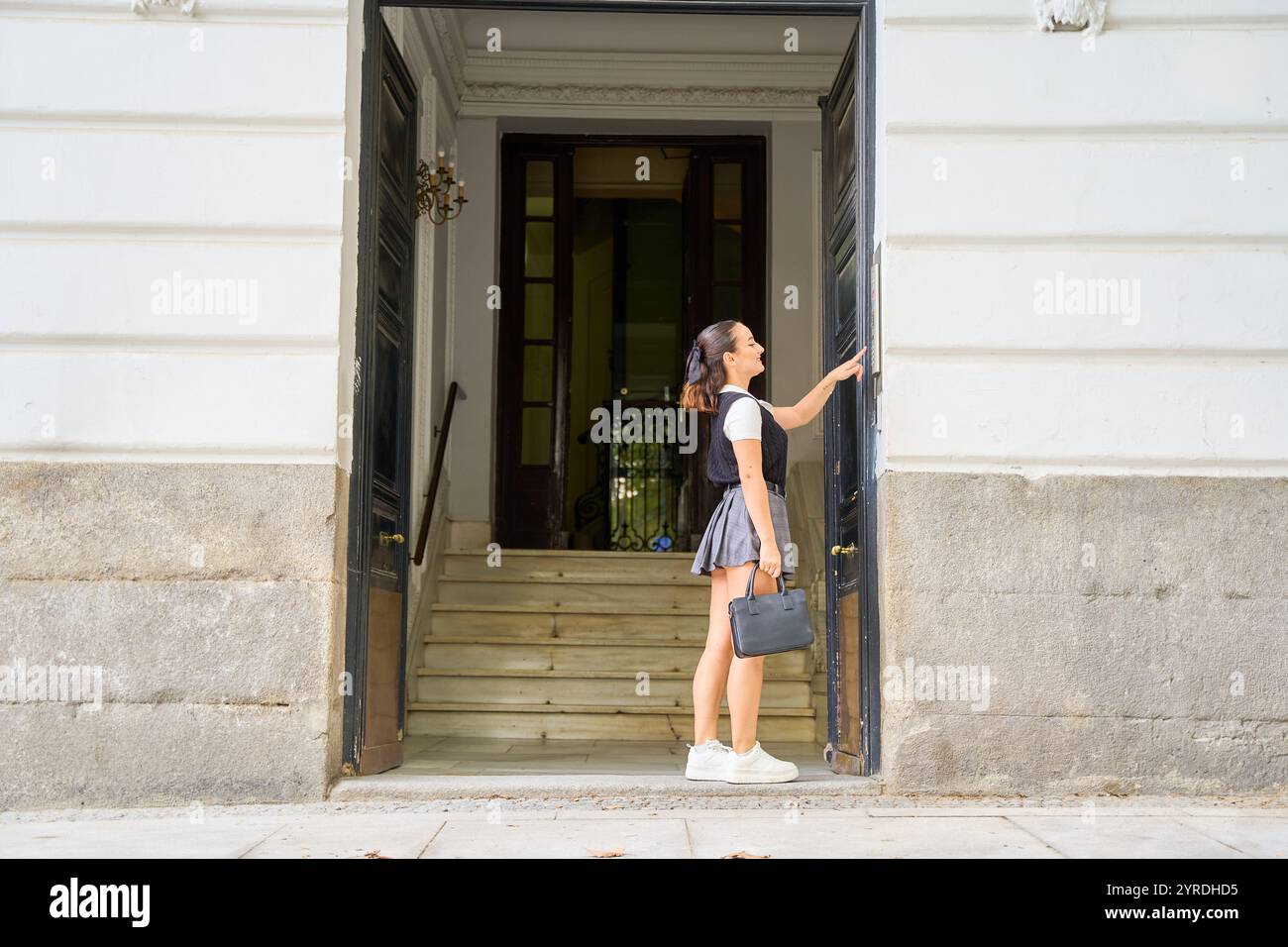 Young woman pressing intercom outside a building entrance Stock Photo ...