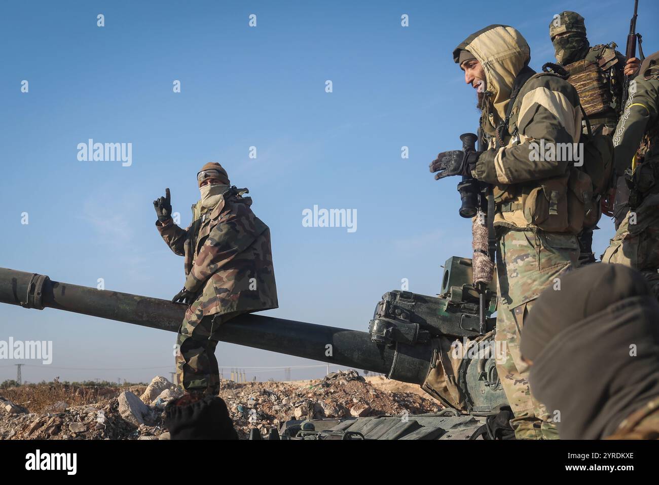 Syrian opposition fighters stand atop a seized military armored vehicle ...