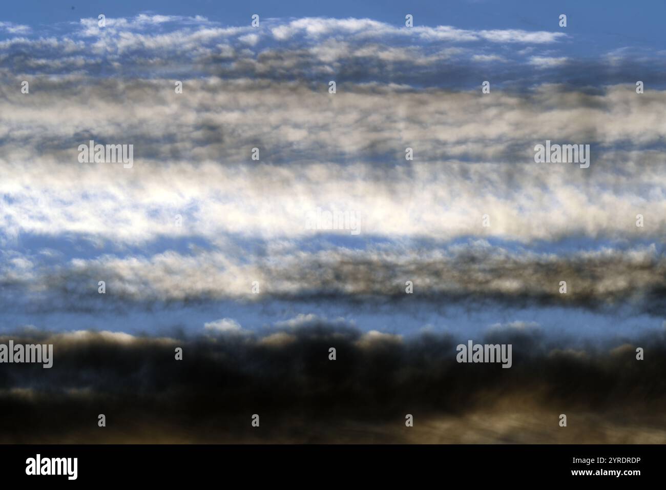 High cirrus clouds lit from a low sun are arranged in ethereal plains ...