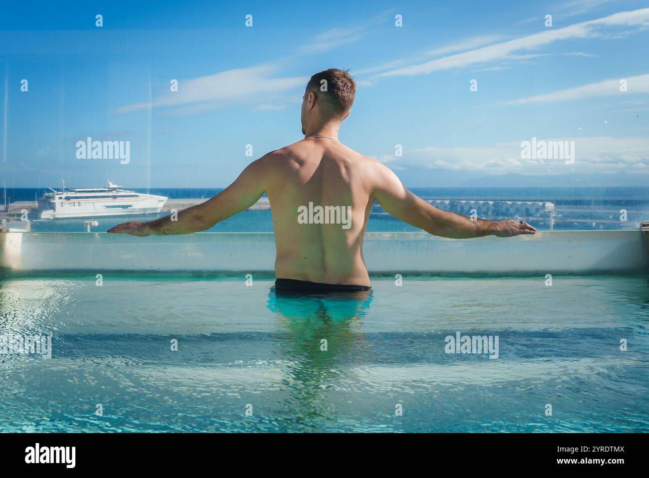 Man in Infinity Pool Overlooking Ocean with Yacht in Background Stock ...