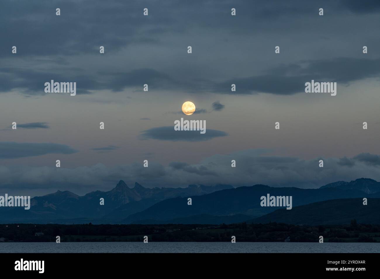 The almost full moon behind the Alps on a cloudy day Stock Photo - Alamy