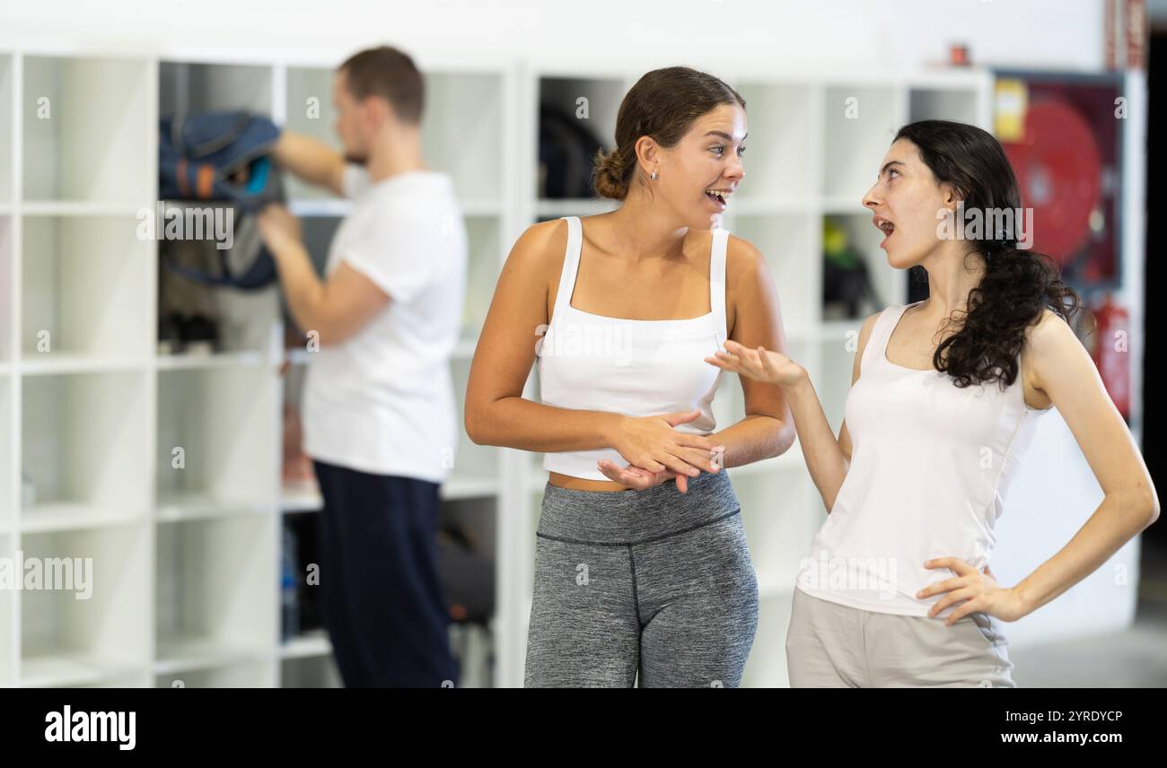 Two female climbers laughing and sharing stories in climbing gym locker ...
