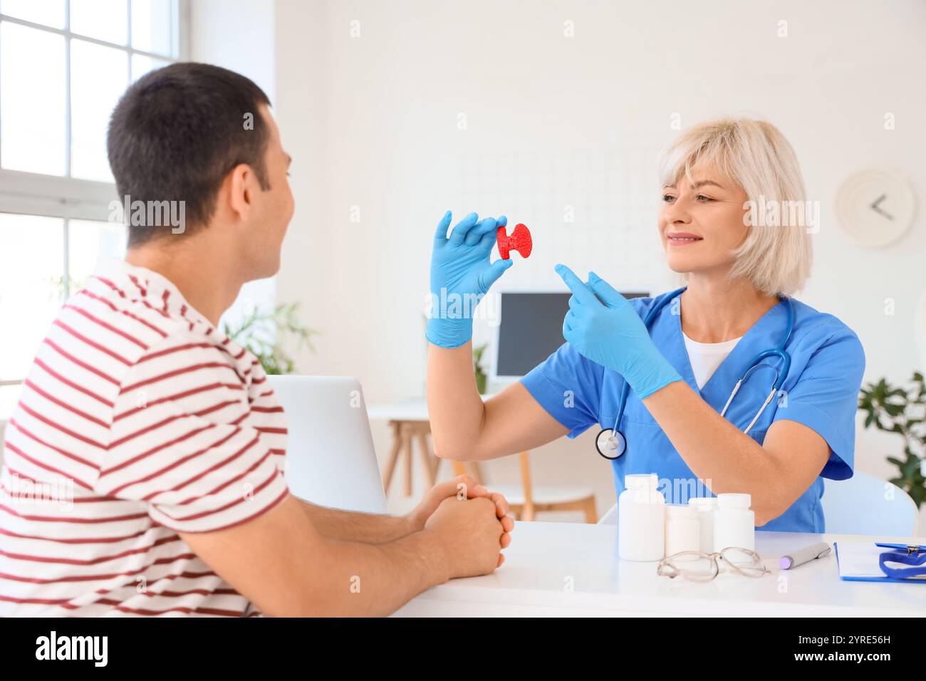 Female endocrinologist showing thyroid gland model to man in clinic ...