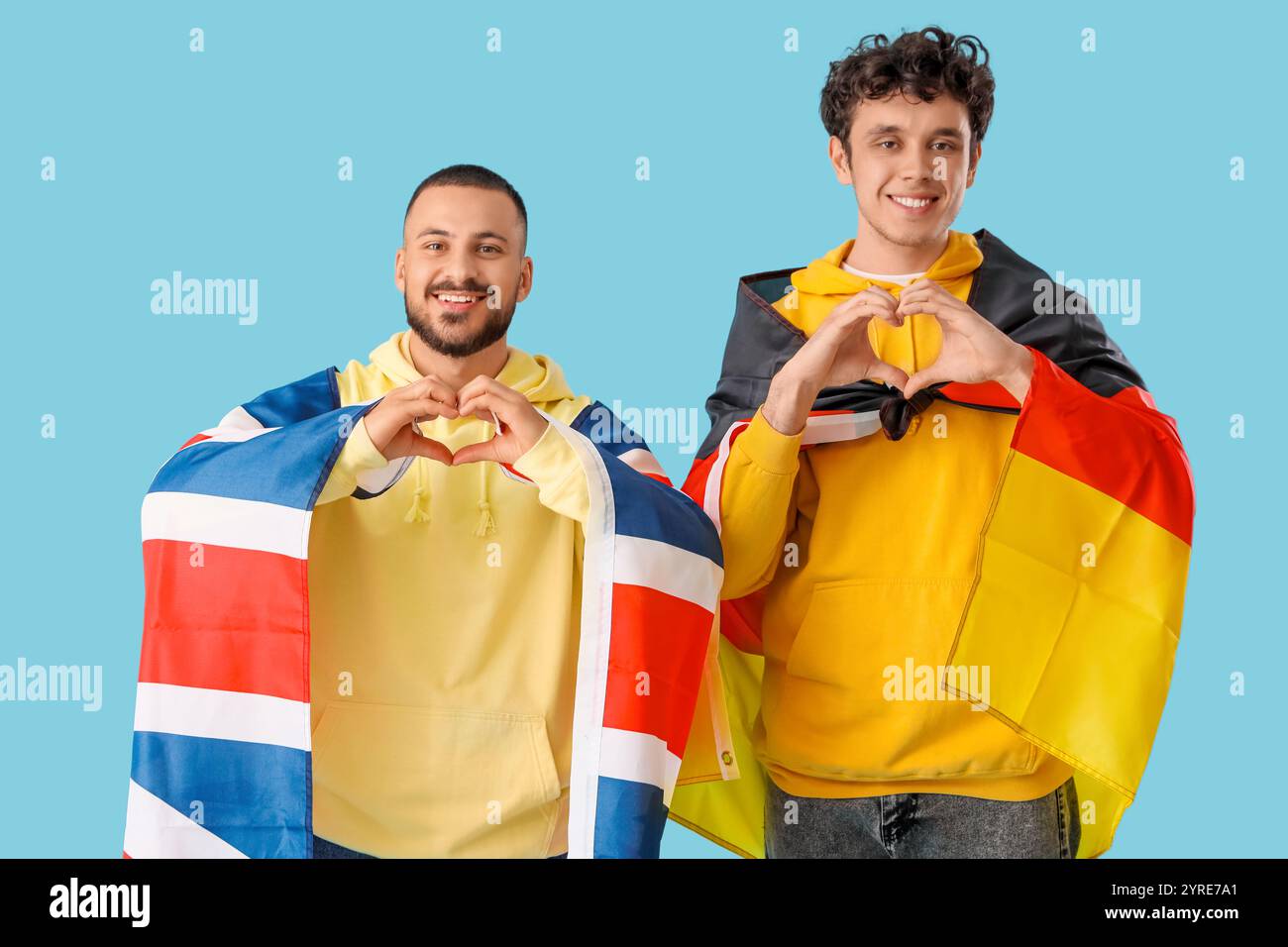 Handsome young happy men with flags of Germany and UK showing heart ...