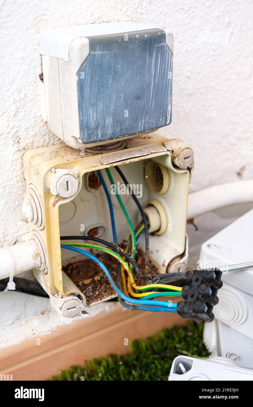 A worn and damaged outdoor electrical cable box is shown, with its ...