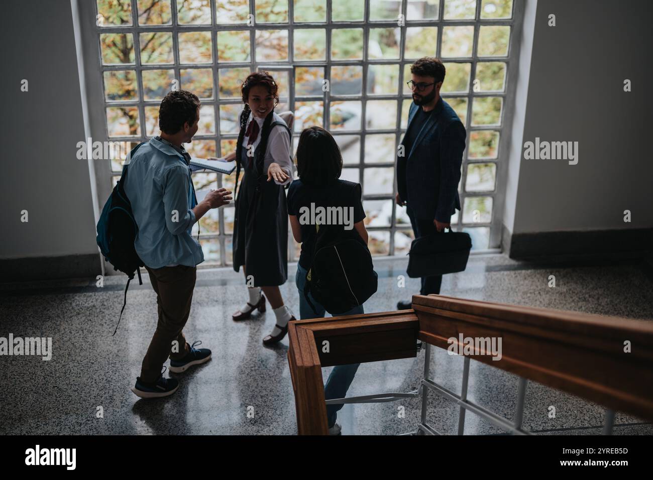 Group of students consulting with professor in university hallway Stock ...