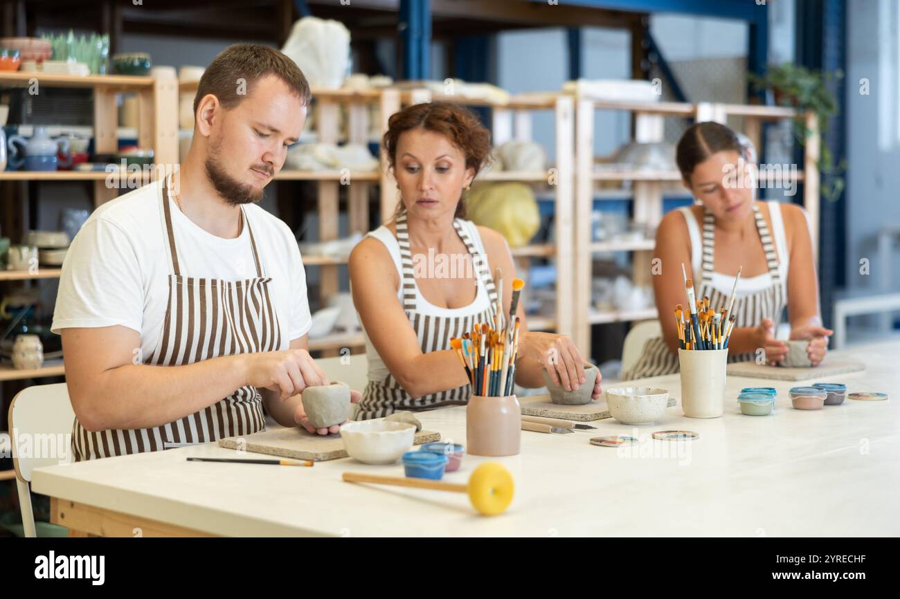 Three pottery workshop workers sculpt from raw clay Stock Photo - Alamy