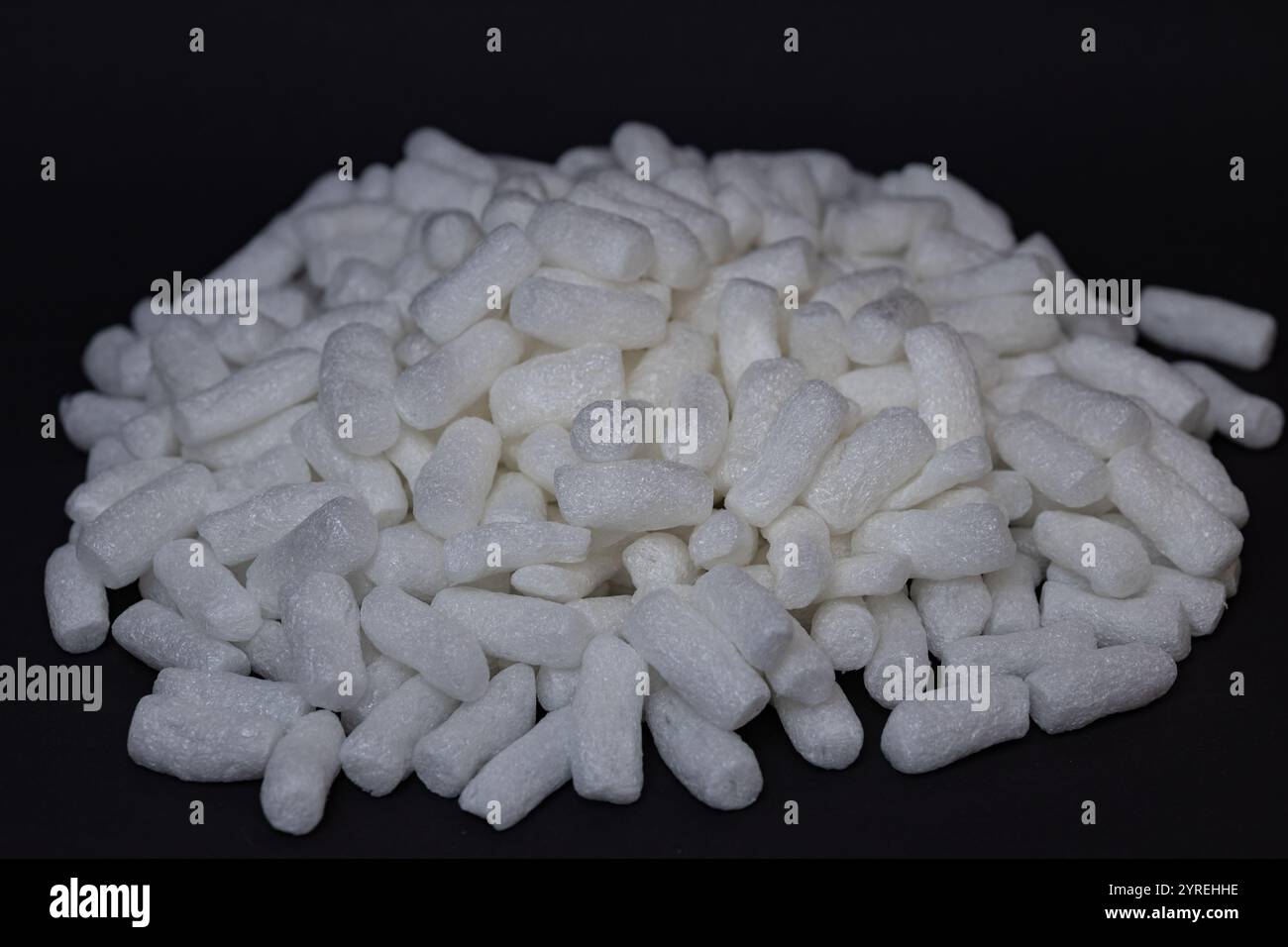 Close-up pile of white polystyrene foam packing peanuts on dark background, ideal for cushioning ...