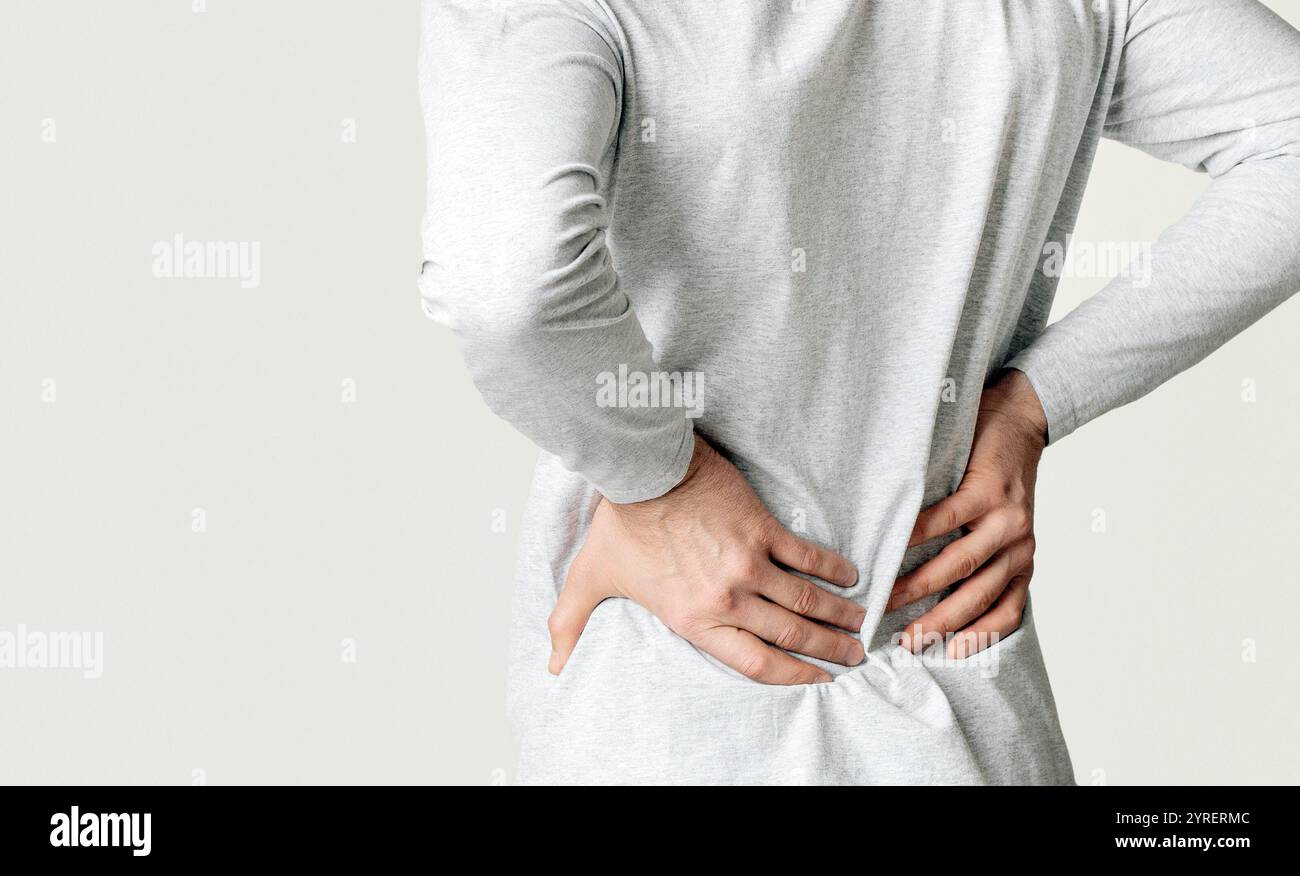 Kidney pain concept. Man presses hands to his back Stock Photo - Alamy