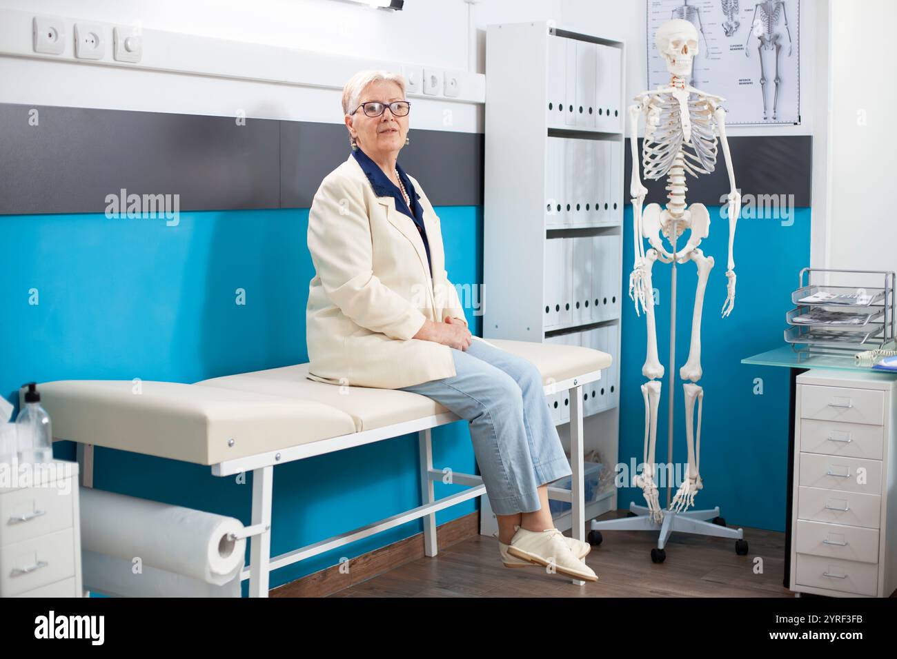 Portrait of elderly white woman patiently seated on examination bed ...