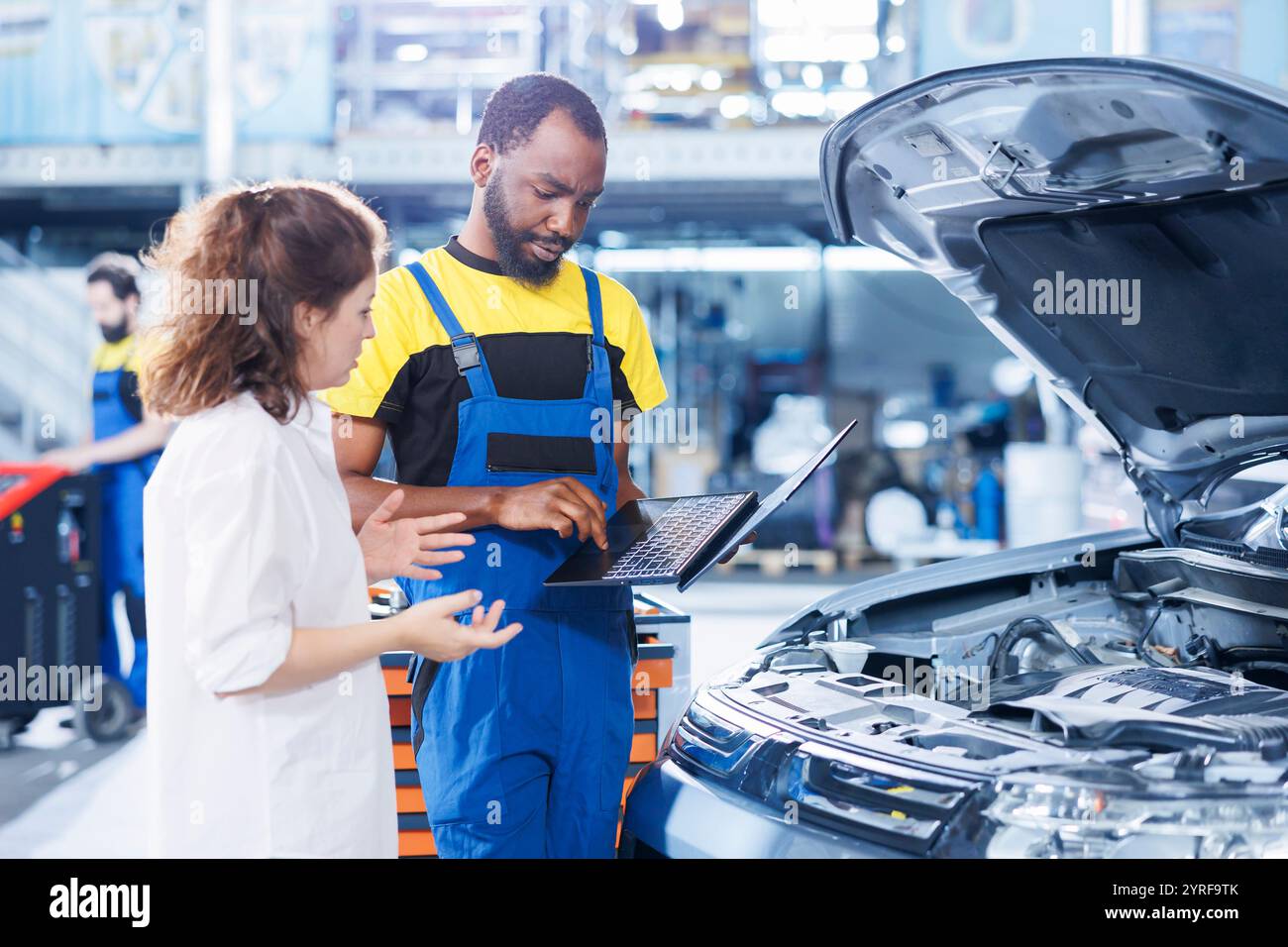 Mechanic in car service uses laptop to calculate invoice after fixing ...