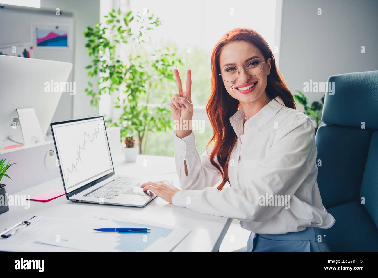 Photo of attractive young woman working netbook show v-sign wear ...