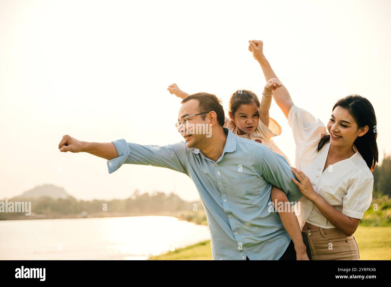 Asian family child girl piggyback riding back on father raising hands ...