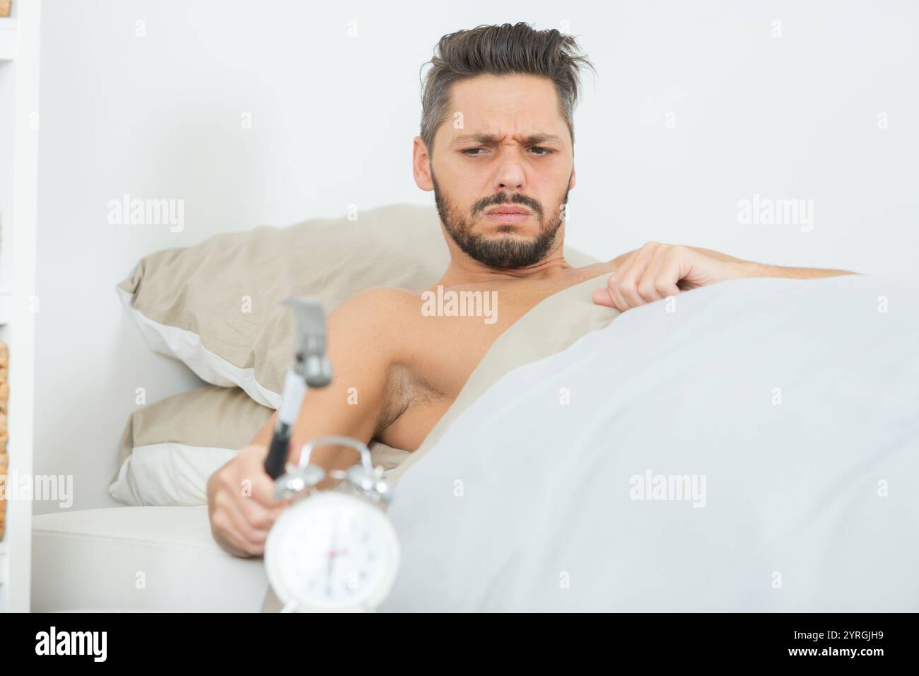 sleepy young man breaking alarm with a hammer Stock Photo - Alamy