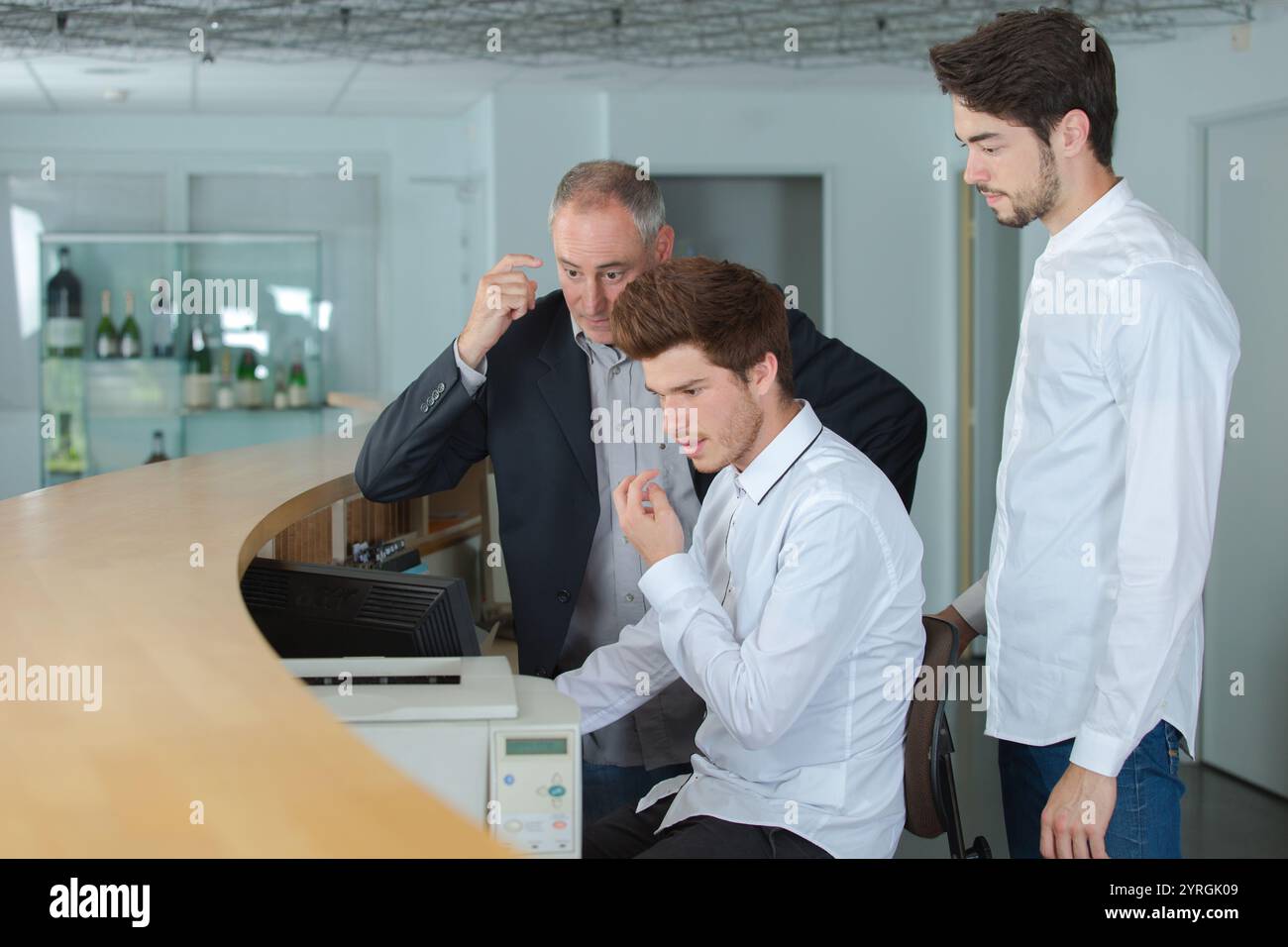 men training behind reception desk Stock Photo - Alamy