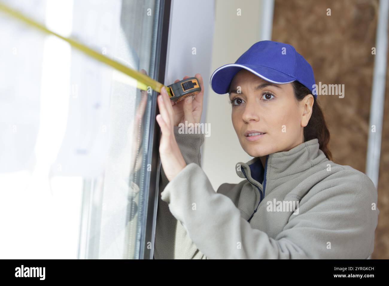 attractive happy woman measuring a window with a tape Stock Photo - Alamy