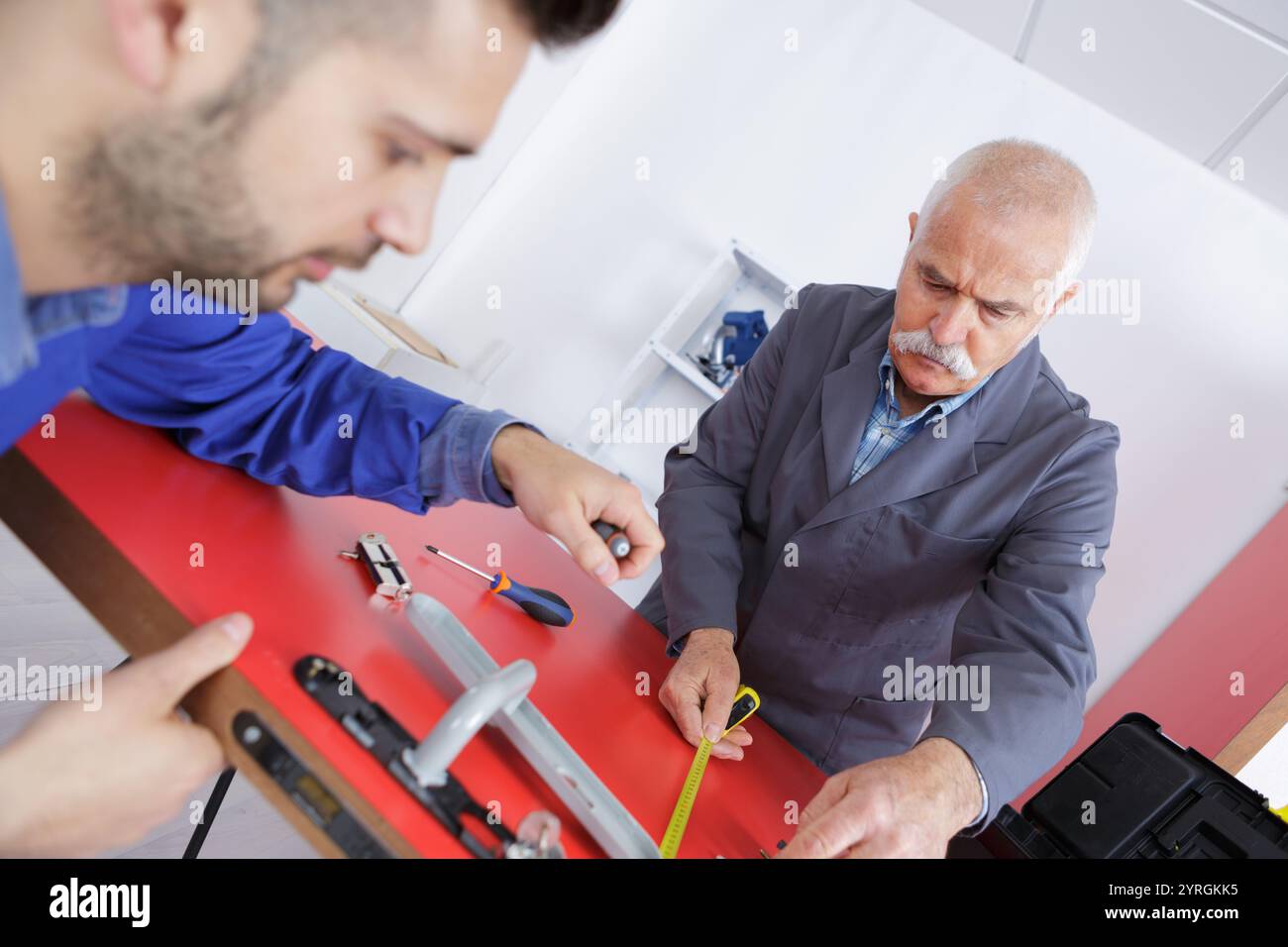 apprentice and master measuring door Stock Photo - Alamy