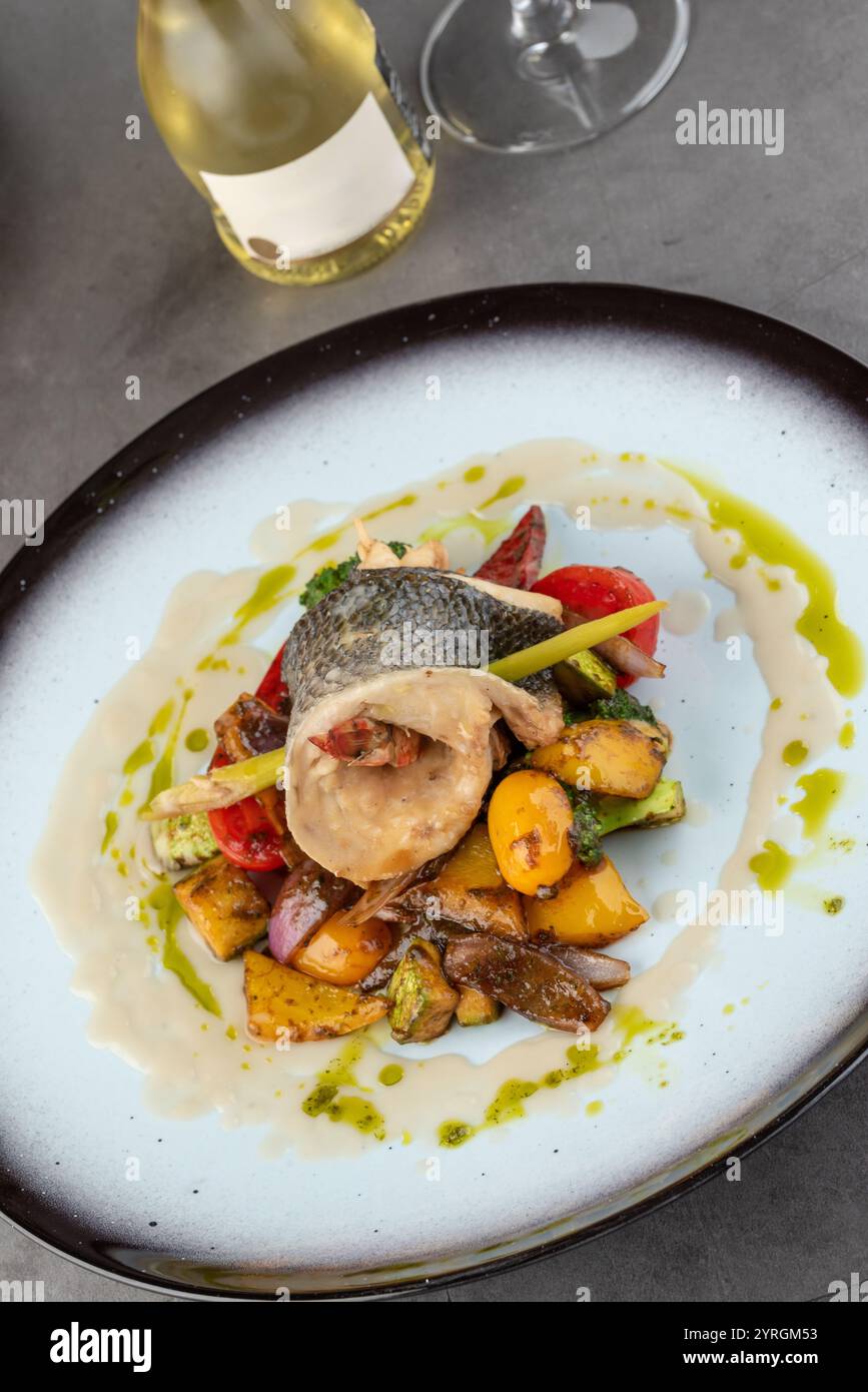 Shrimp wrapped in sea bass on various vegetables on a porcelain plate ...