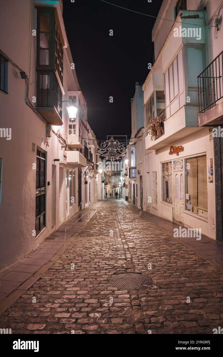 A narrow cobblestone street in Tarifa, Spain, features whitewashed ...