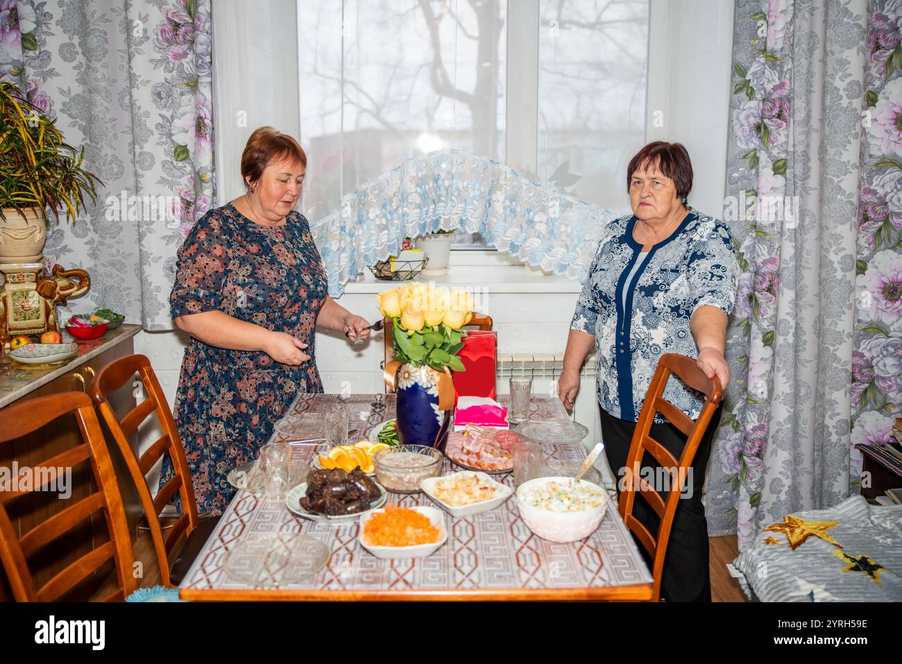 Two Russian women, aged 70 and 60, prepare a festive table with ...