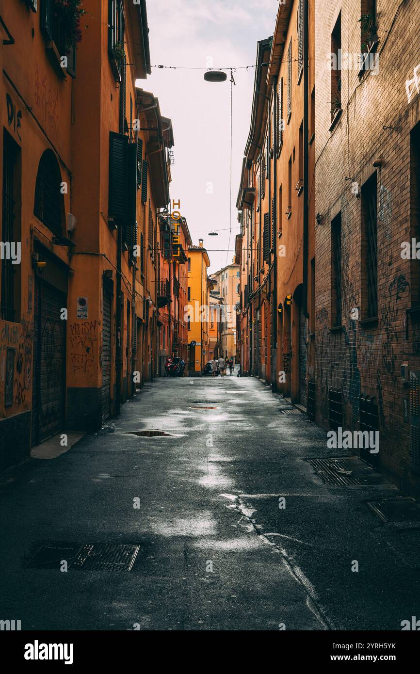 Wet street in bologna, italy with old buildings, graffiti, and puddles ...
