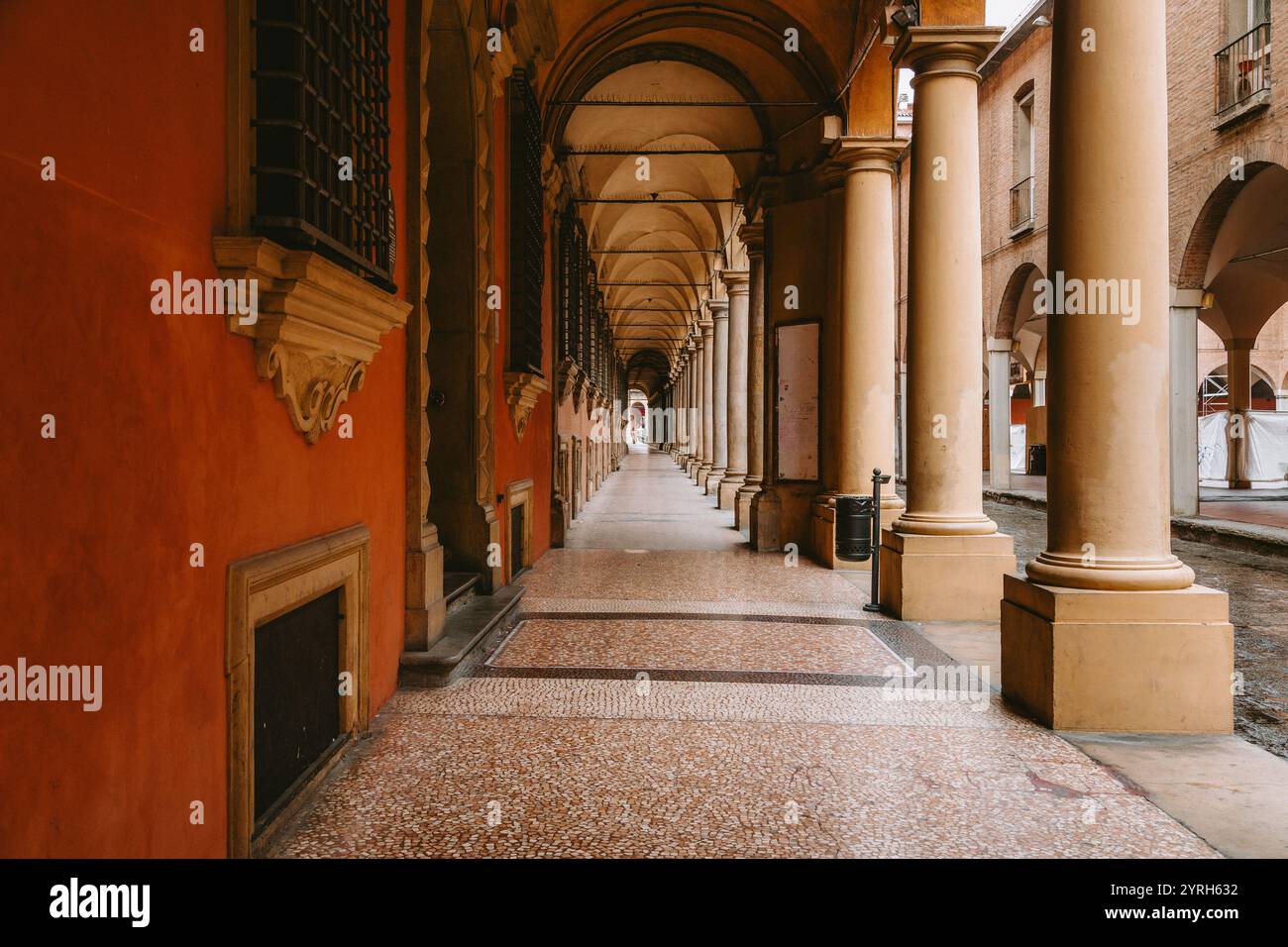 Warm sunlight illuminates the long, empty colonnade with its repetitive ...