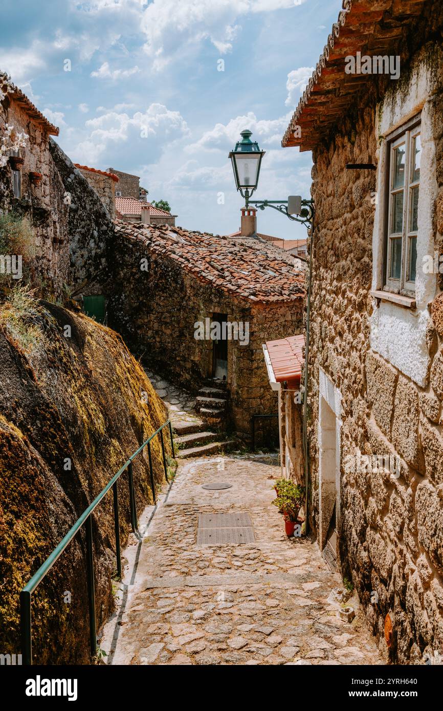 Stone houses and large boulders line a narrow cobblestone street in ...