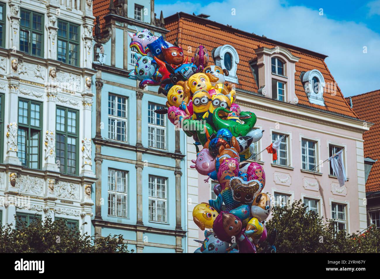 Cartoon character balloons floating in front of colorful buildings in ...