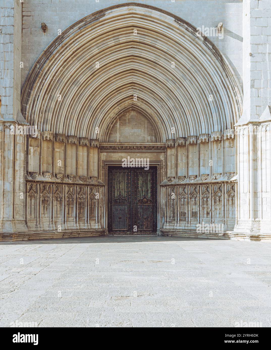 The sunlight highlights the intricate stone archway and weathered ...