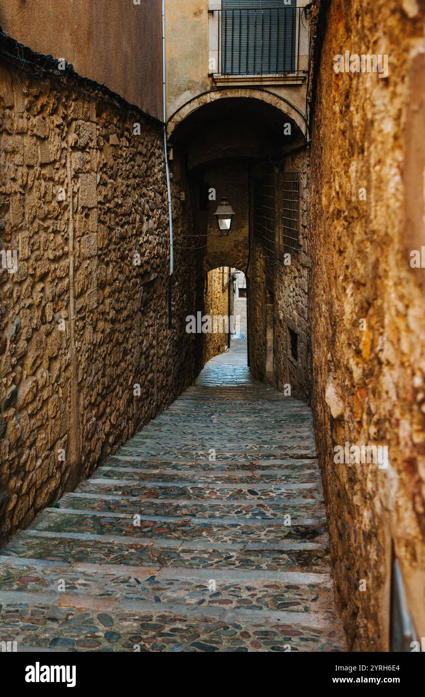 Stone steps ascend through a narrow, arched passageway in girona's old ...