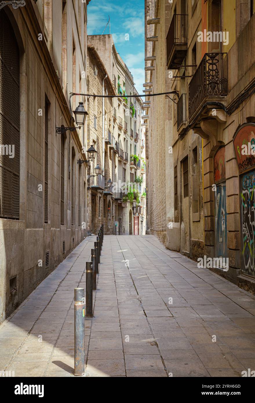 Stone paved narrow alley rising between old buildings with balconies ...