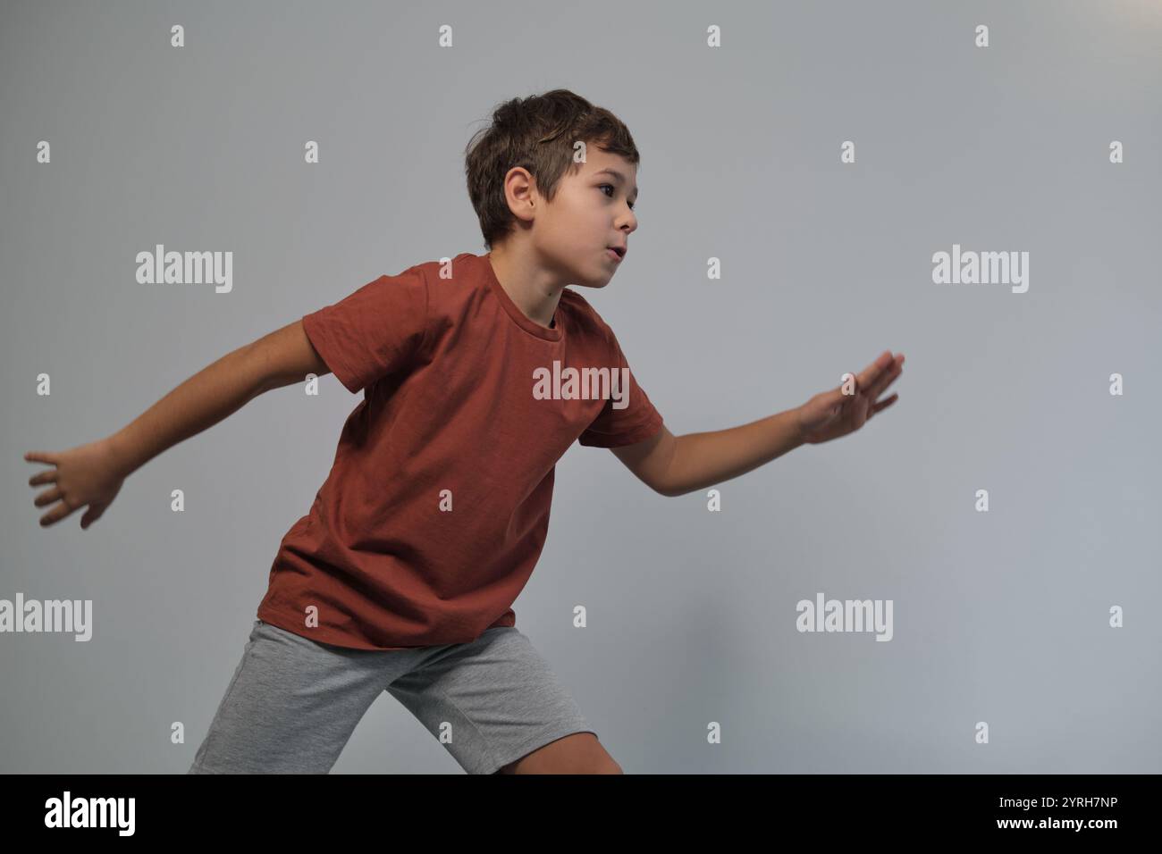 A young boy in an energetic stance, appearing ready to leap or run ...