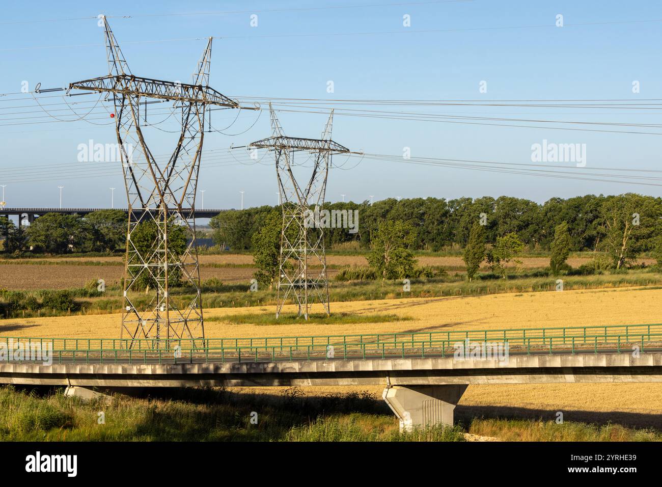 Metal electricity pylons transporting energy across fields and over a ...
