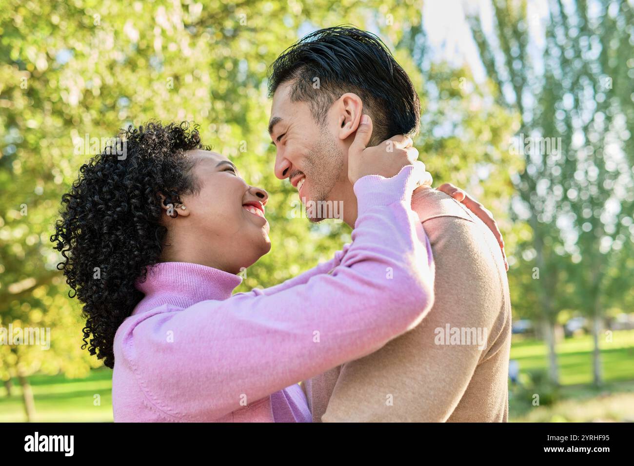 A loving couple shares a joyful embrace in a sunny park They smile ...
