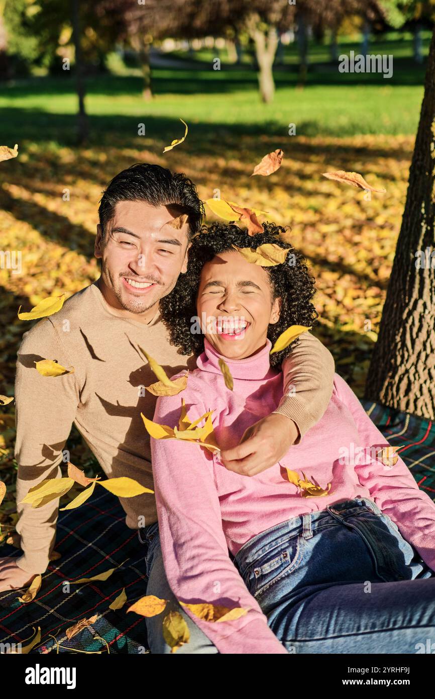 A cheerful couple sits together on a picnic blanket, surrounded by ...