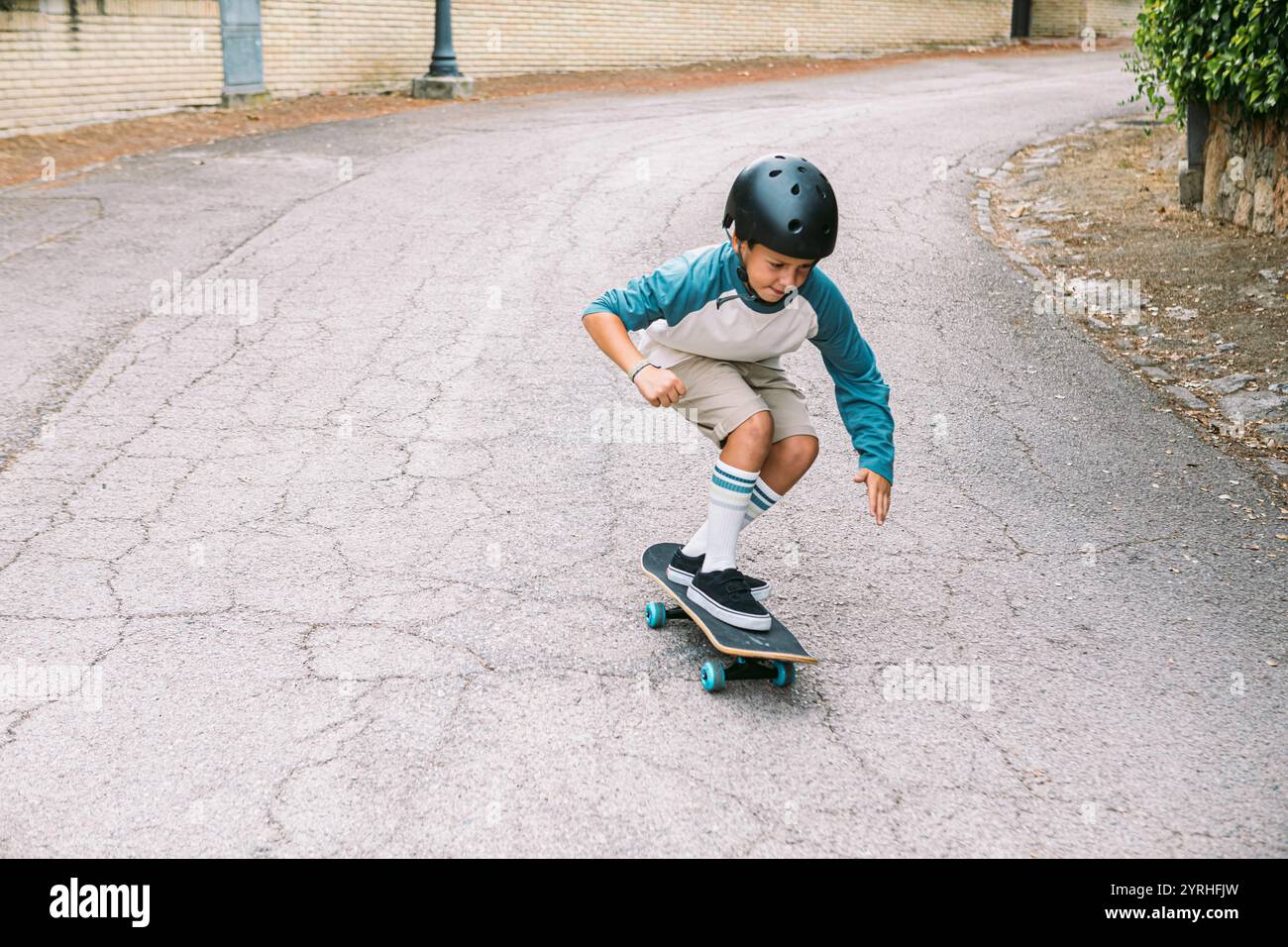 A young boy skillfully rides his skateboard on a curved path, wearing a ...
