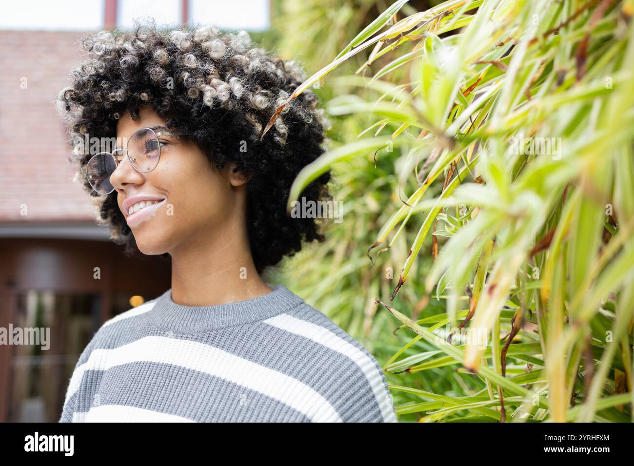 A mixed race woman with vitiligo and curly hair, wearing glasses and a ...
