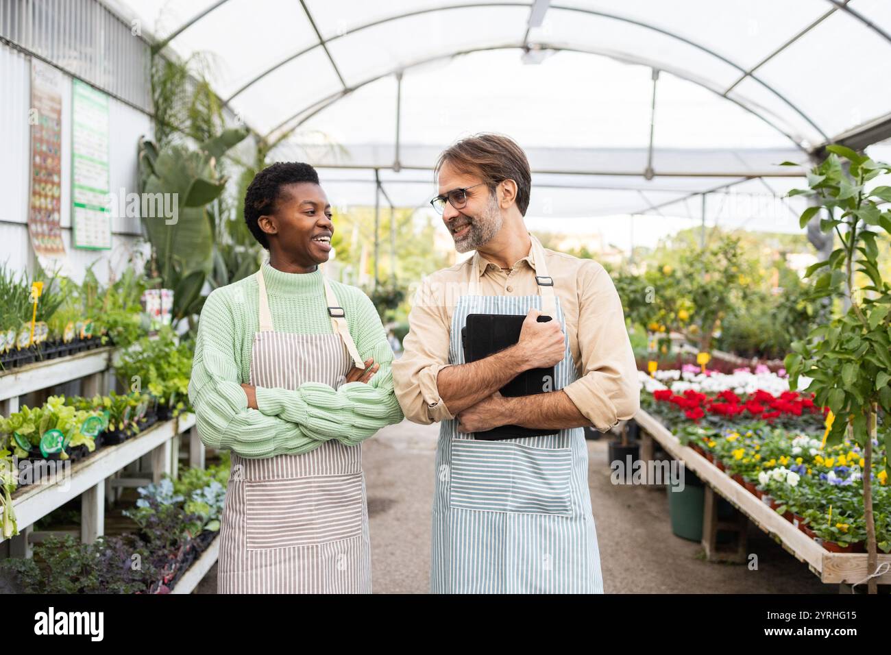 Two friendly staff members converse in a bright garden store ...