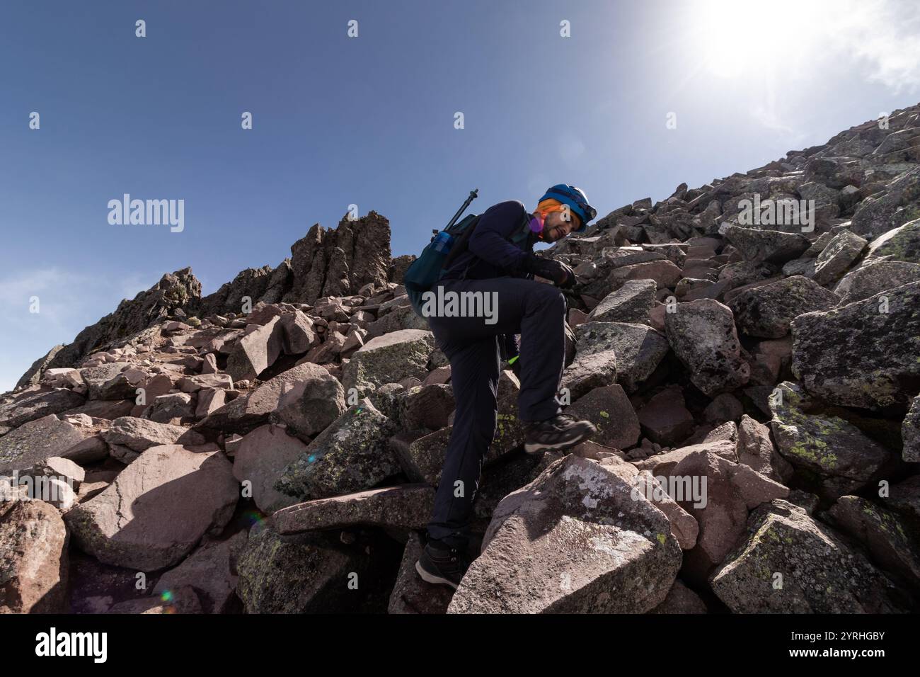 A climber, equipped with a backpack and helmet, navigates the rocky ...