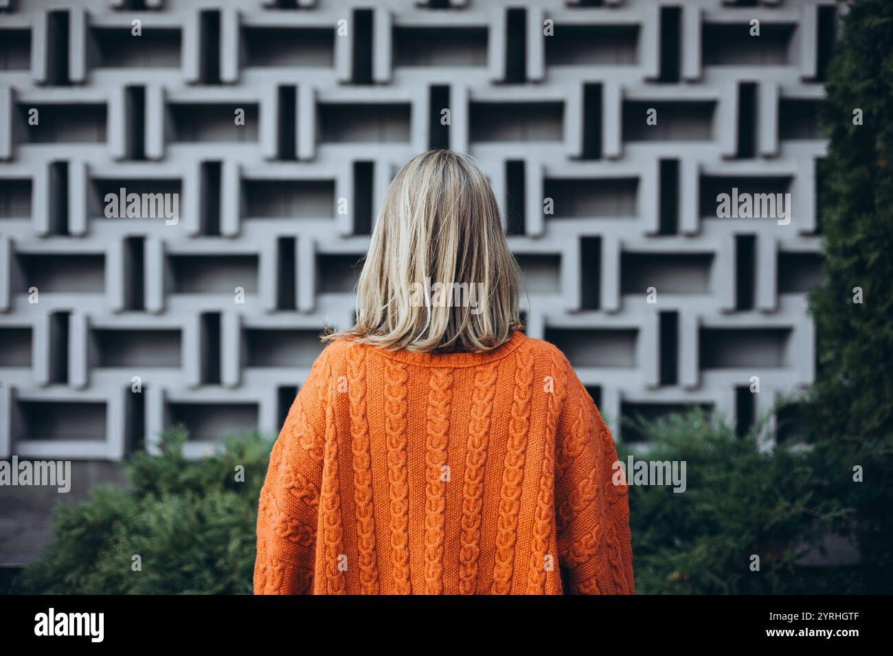 A female student stands facing a modern geometric wall with intricate ...
